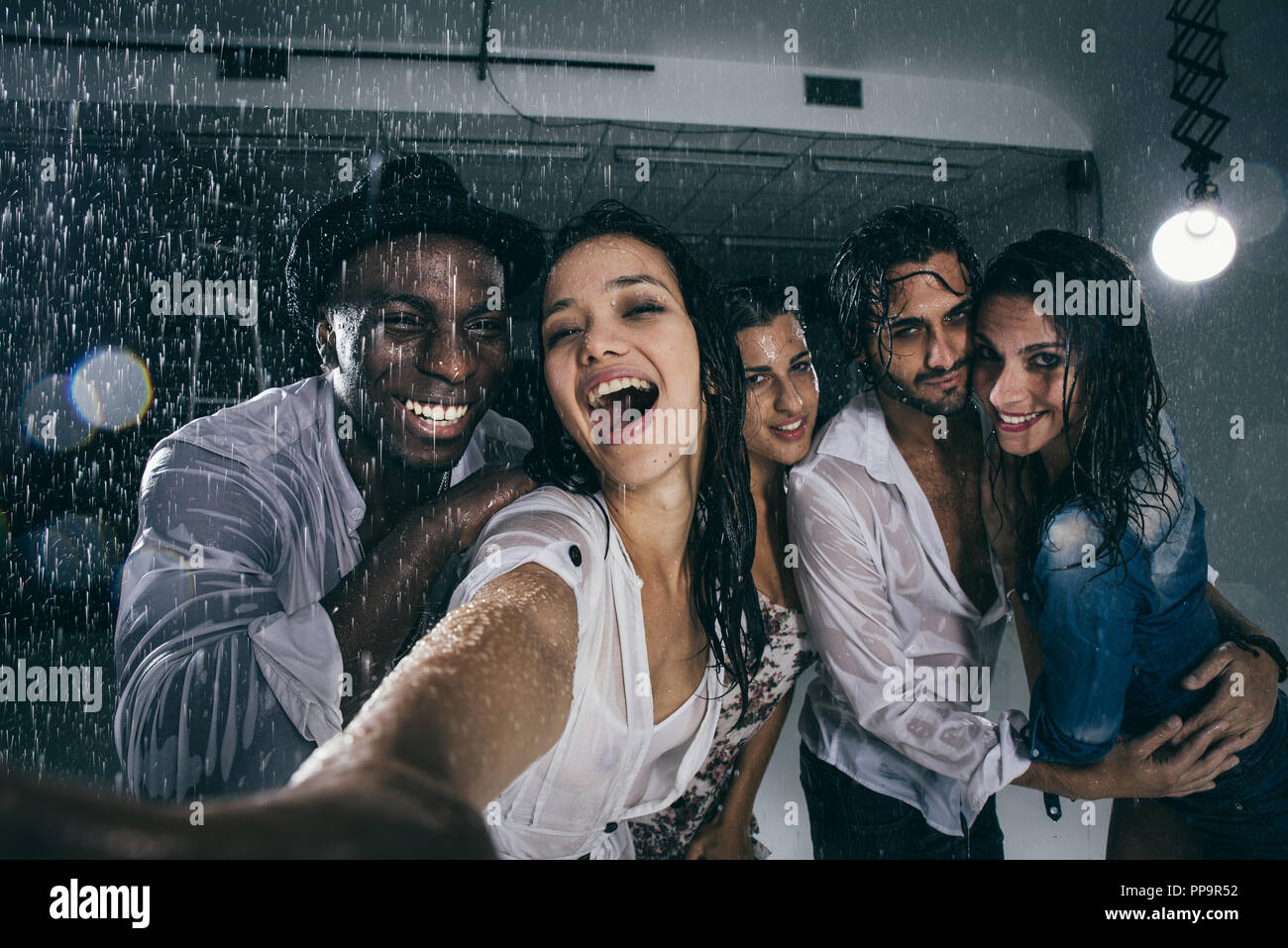 Group of friends dancing under the rain - Multiethnic people having ...
