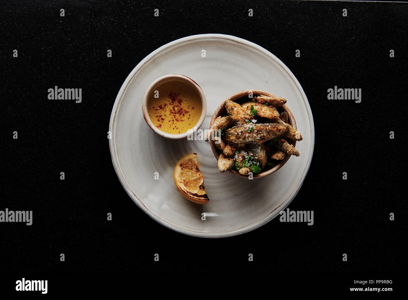 delicious crispy whitebait fish in bowl on white plate with charred ...