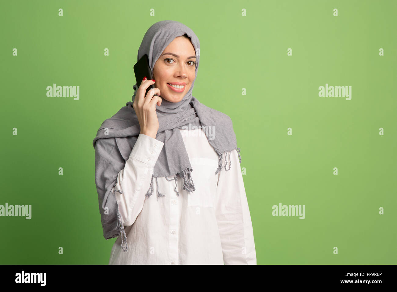 Happy arab woman in hijab with mobile phone. Portrait of smiling girl ...