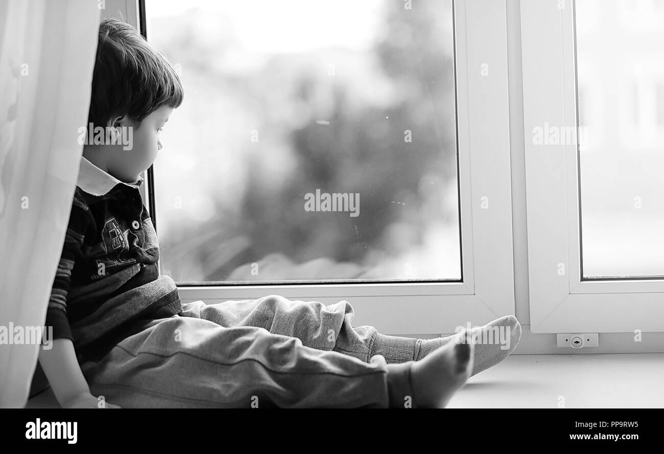 The little boy is reading a book. The child sits at the window a Stock ...