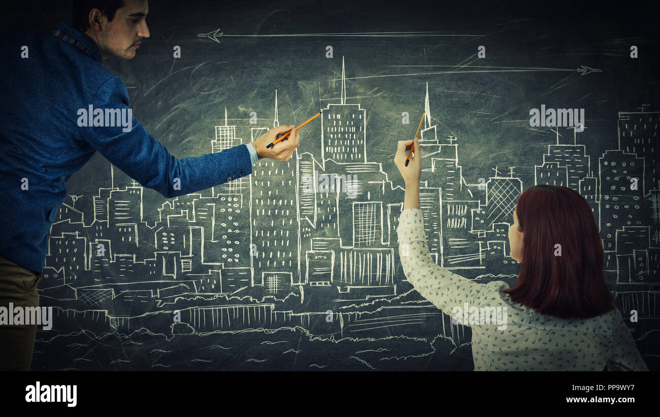 Man and woman sharing thoughts together drawing a city on a blackboard ...