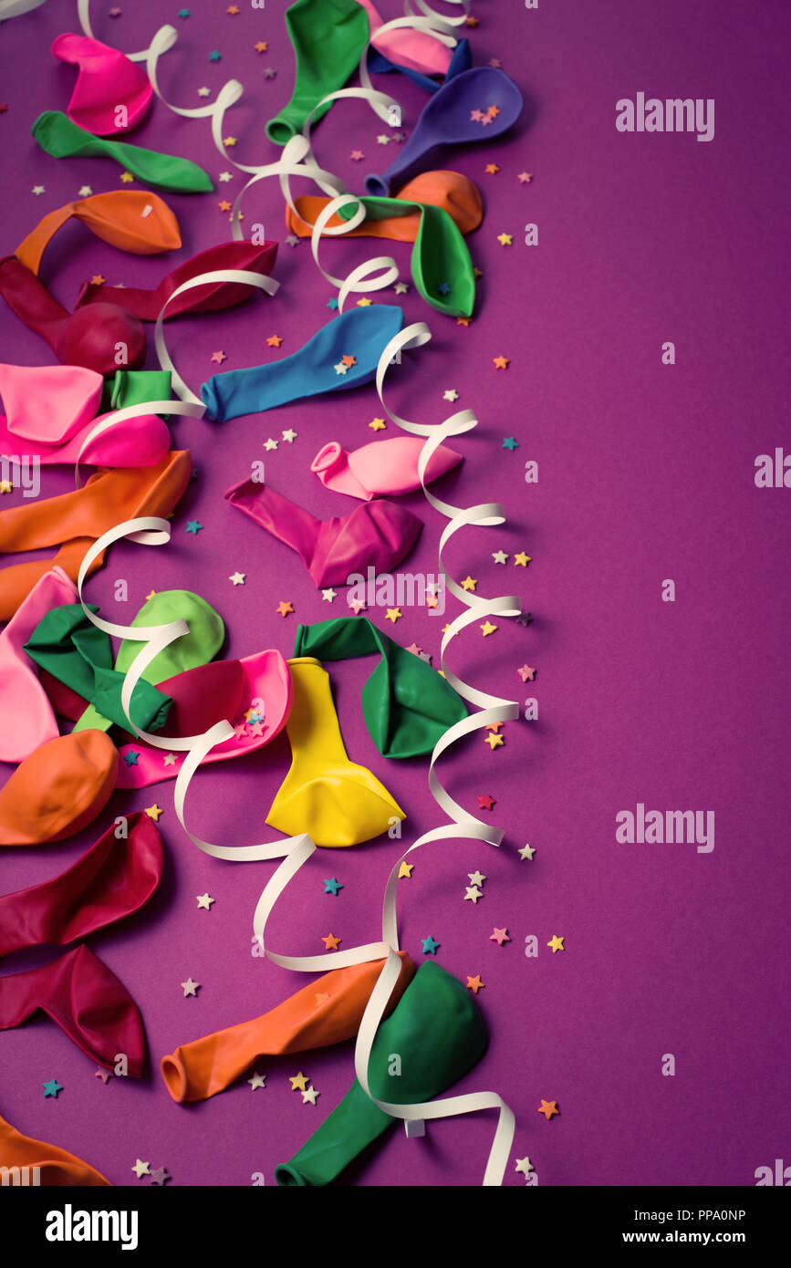 Festive background of purple material colorful balloons streamers ...