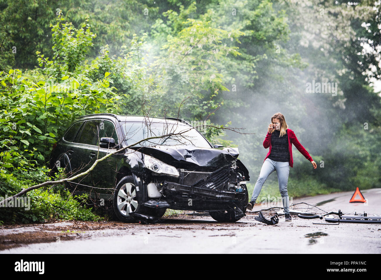 An angry young woman with smartphone by the damaged car after a car ...