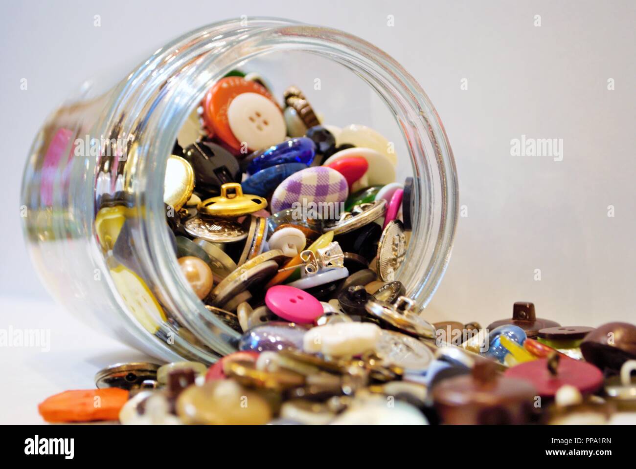 jar full of multi colored buttons overflowing Stock Photo - Alamy