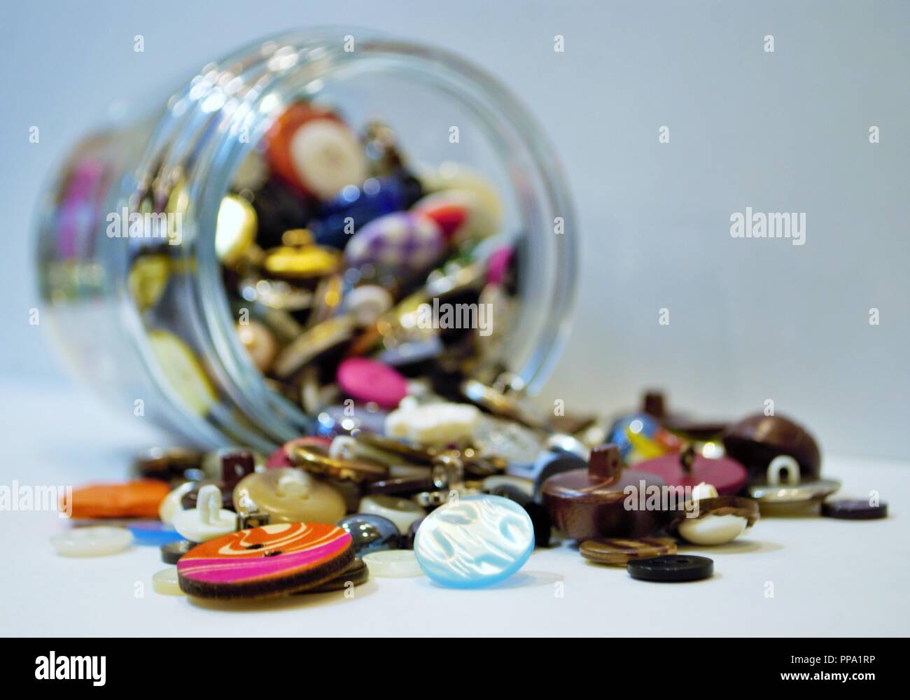 jar full of multi colored buttons overflowing Stock Photo - Alamy