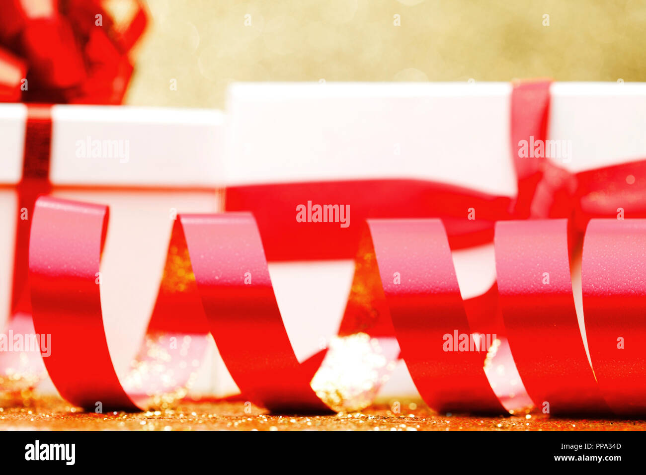 White gift box with red ribbon bow on golden glitter background Stock ...