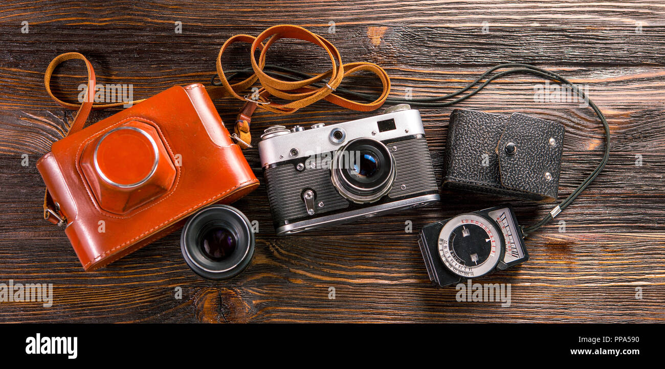 Old film camera, lenses and old exposure meter on a wooden background ...
