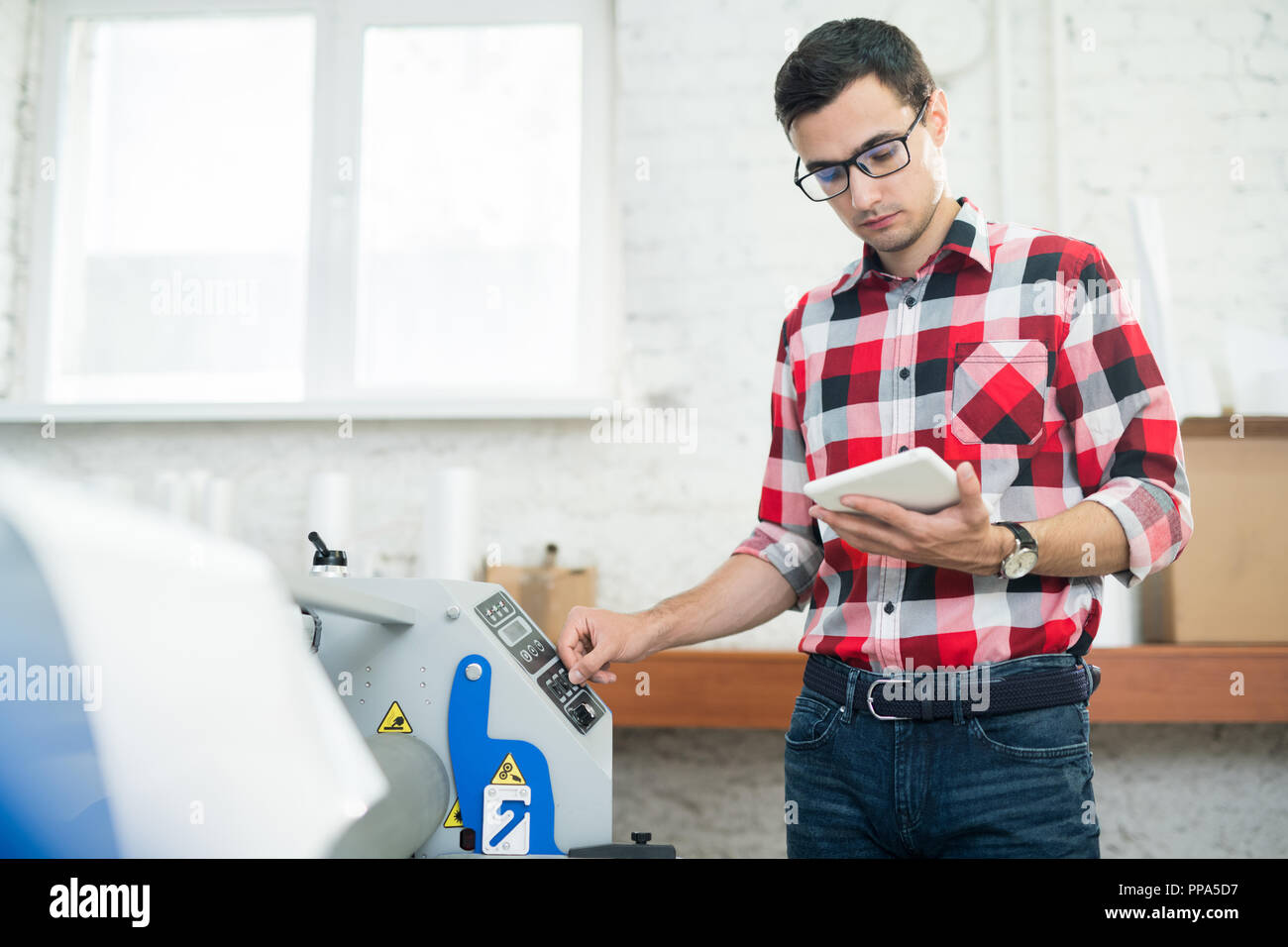 Man watching tablet and using printing machine Stock Photo - Alamy