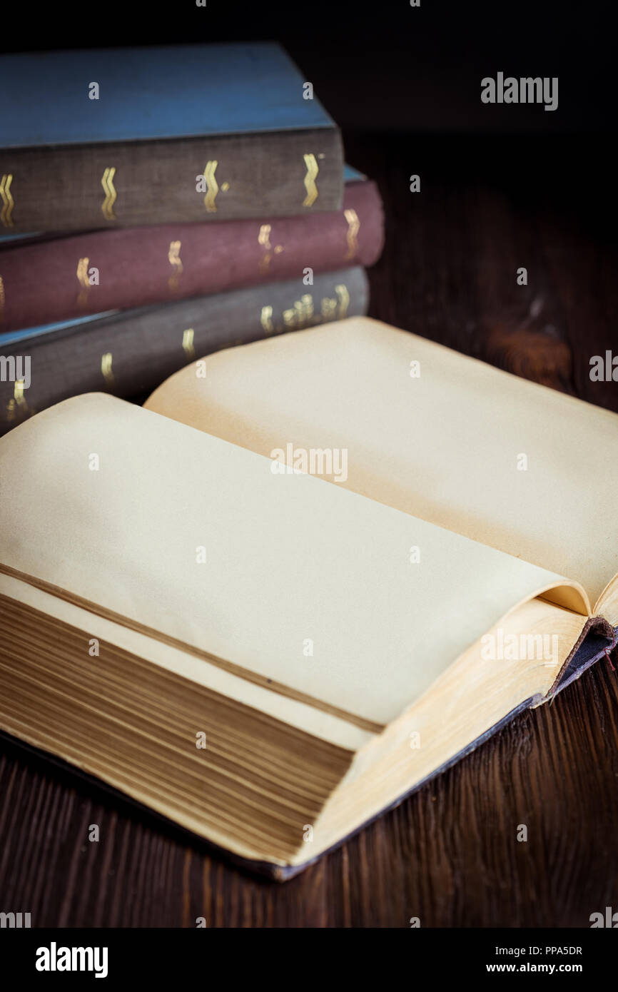 Open old book and a stack of books in the background Stock Photo - Alamy