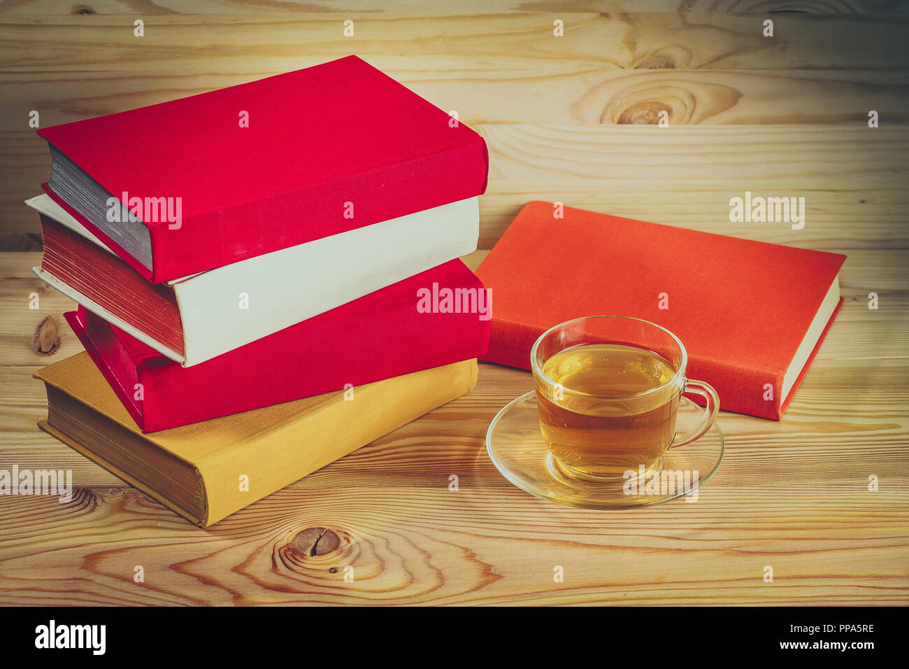 Glass cup with tea and a stack of books with colorful covers. Vintage ...