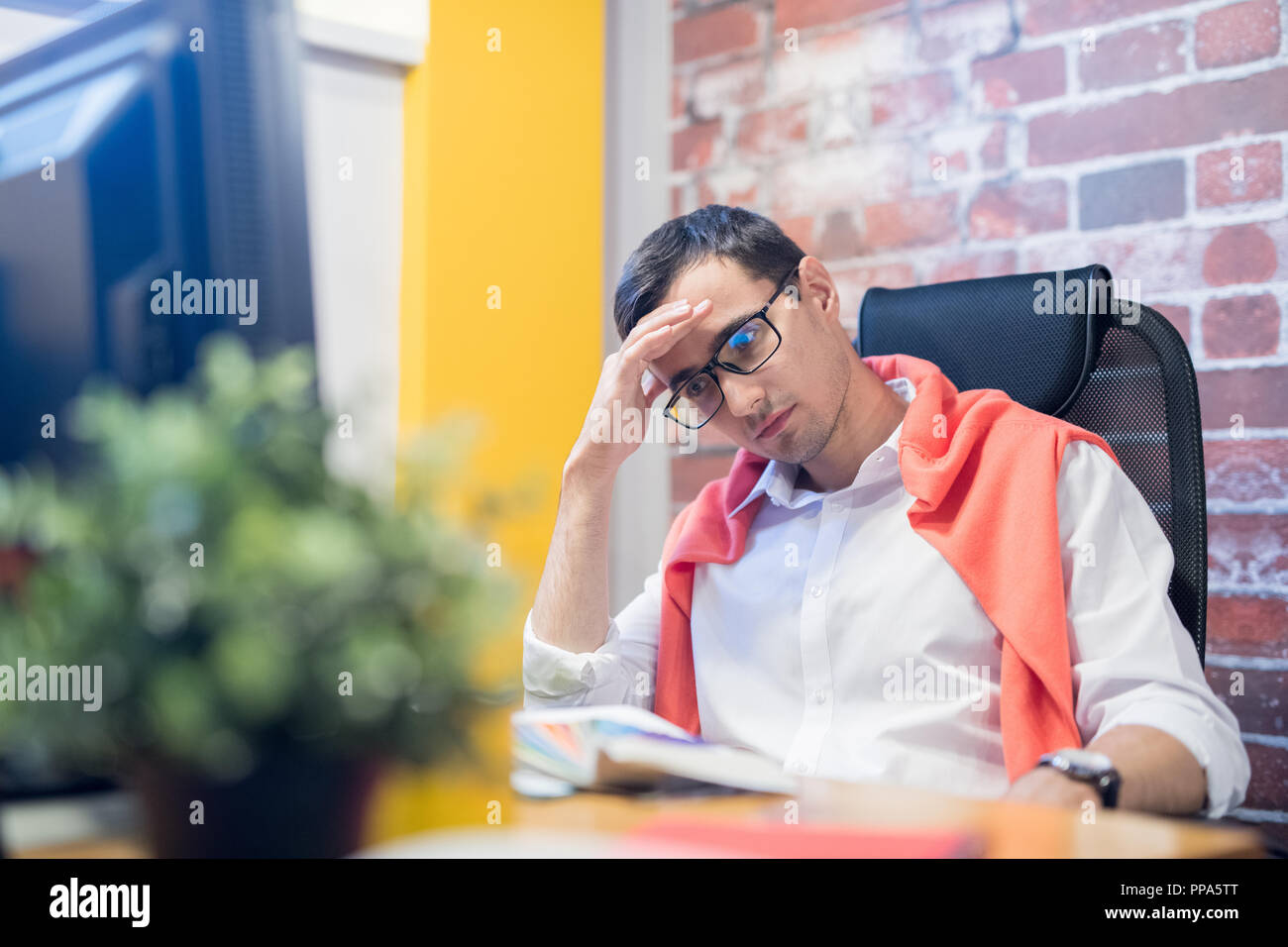 Exhausted young man working in office Stock Photo - Alamy
