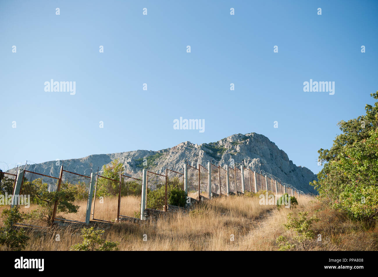 long high fence with barbed razor wire near rocky mountains in Mexico ...