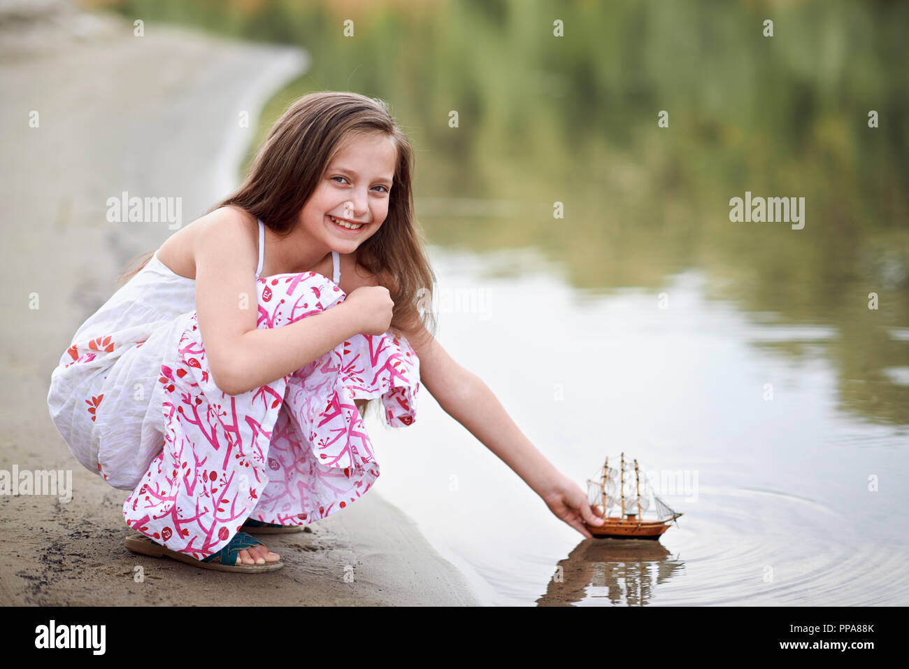 girl playing with a toy sailing ship by the river Stock Photo - Alamy