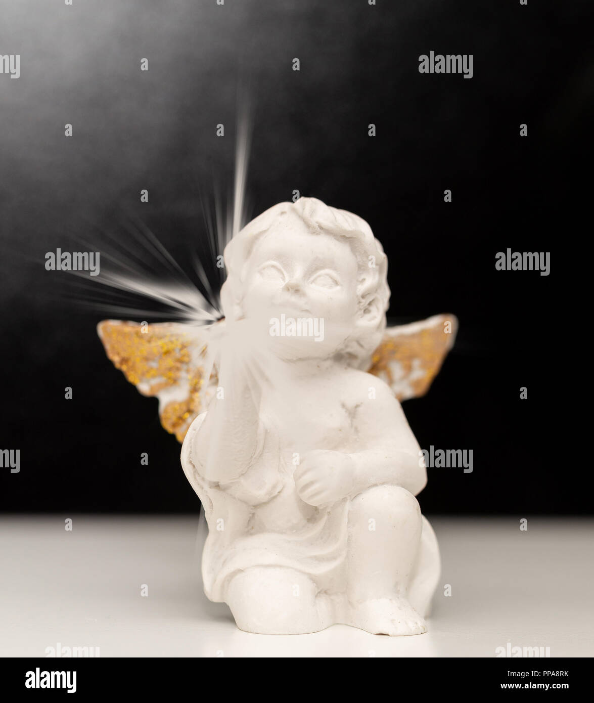 A Little Figure Of Angel With Strong Lights In The Hands. Black ...