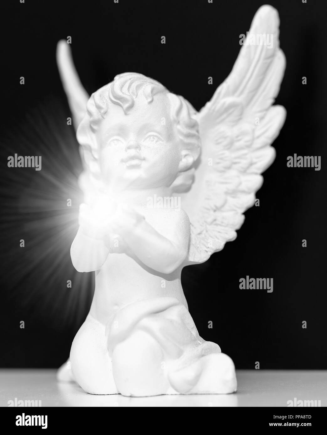 A Little Figure Of Angel With Strong Lights In The Hands. Black ...
