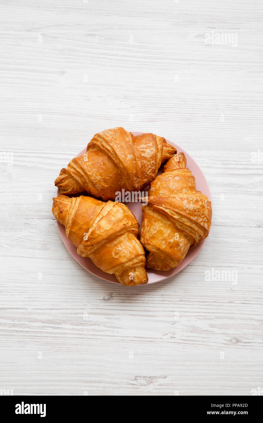 Fresh croissants with golden crust on white wooden background, overhead ...