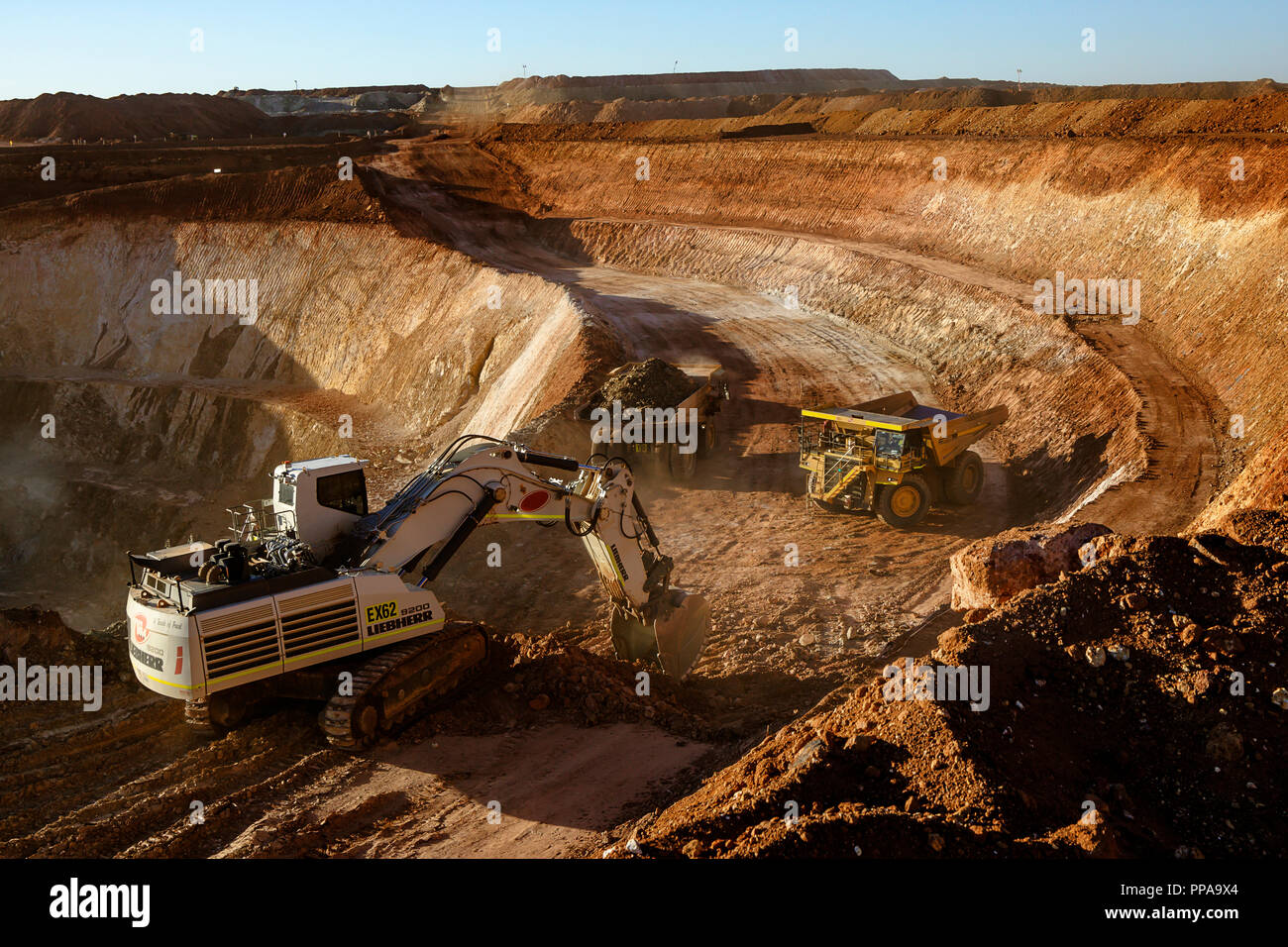 Trucks being loaded with ore by digger in open pit mine, Western ...