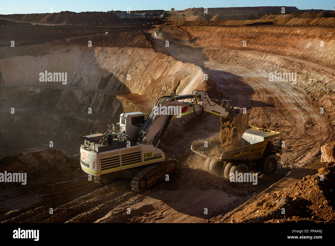 Trucks being loaded with ore by digger in open pit mine, Western ...