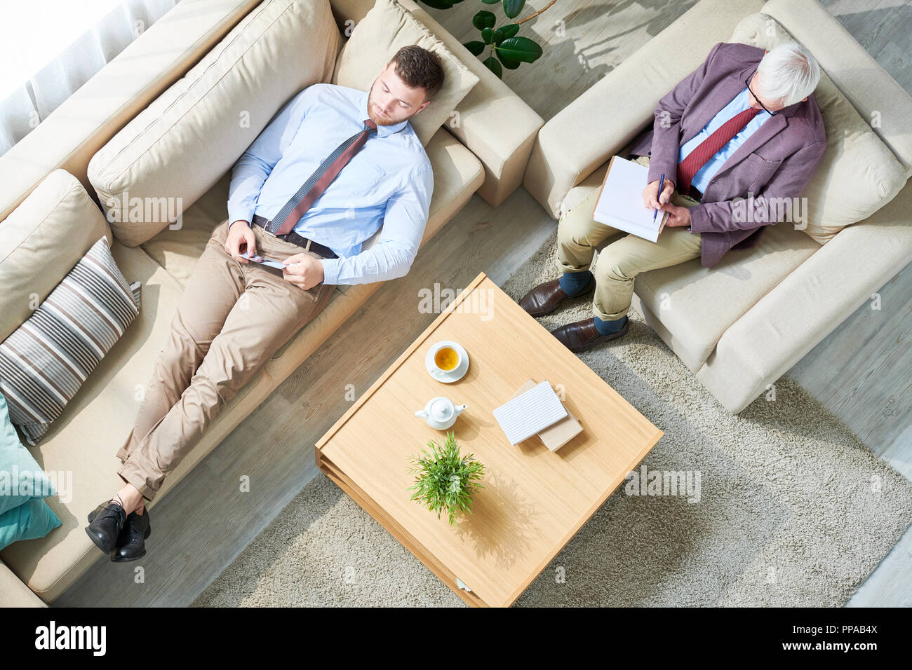 Above view portrait of senior psychologist consulting young man lying ...