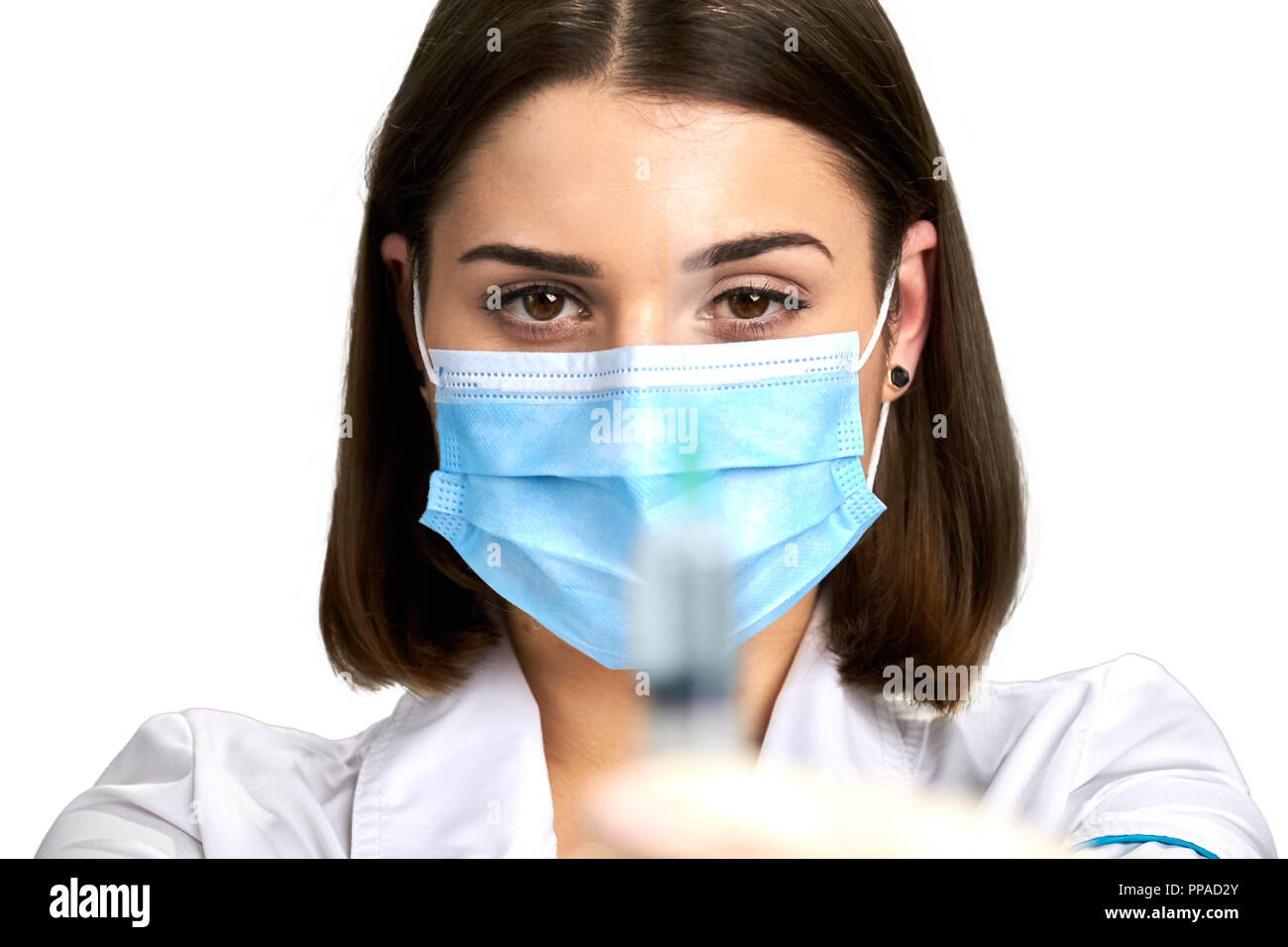 Close up young doctor with injection. Pretty nurse in face mask holding ...