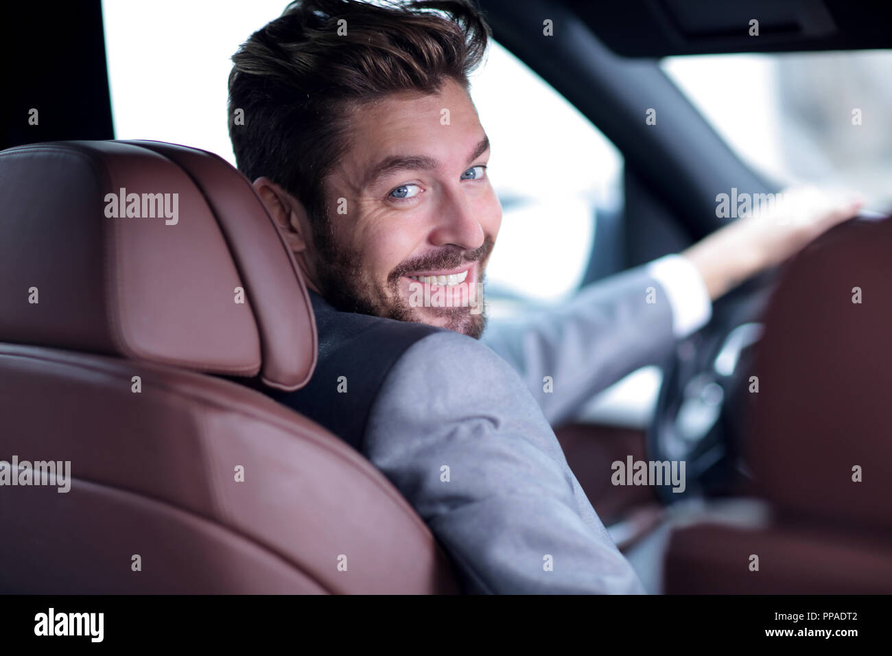 rear view, young man driving his car, looking at camera Stock Photo - Alamy