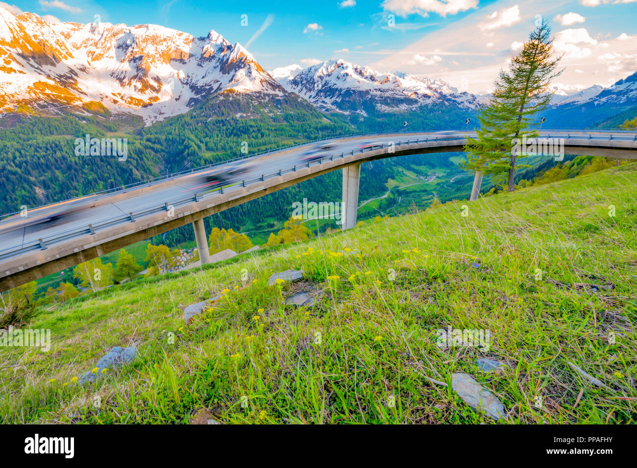 Traffic Over a Curved Mountain Road Bridge and Snow-capped Mountain in ...