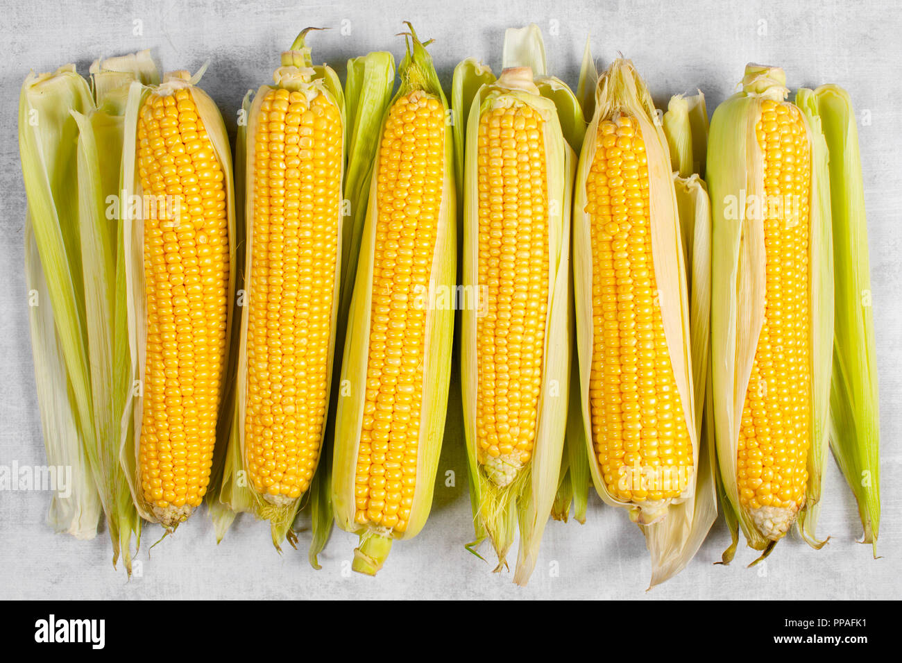 Fresh sweetcorn cobs on the textured grey table, top view Stock Photo ...