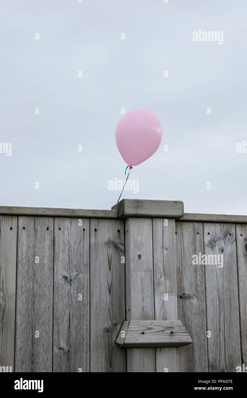 Pink balloon above wooden fence Stock Photo - Alamy