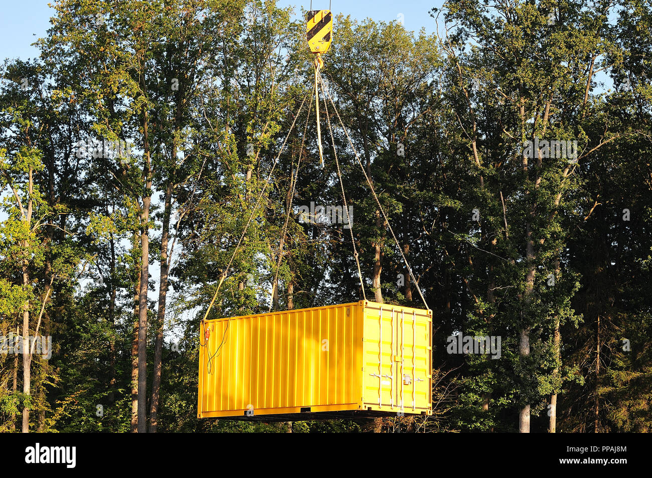 large yellow container hanging at metal chains at hook of a ...
