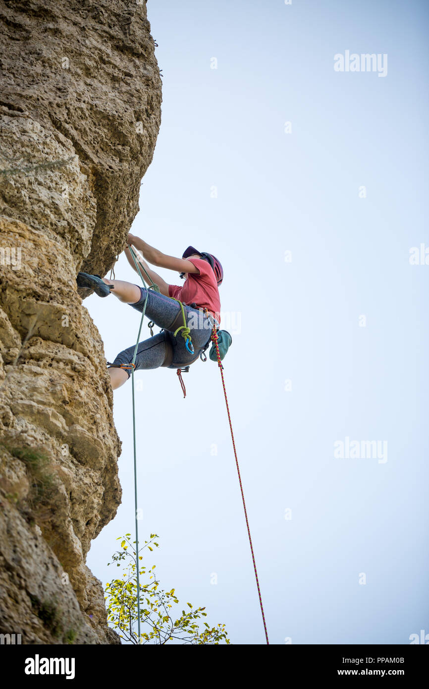 Photo of athlete woman in helmet clambering over rock Stock Photo - Alamy