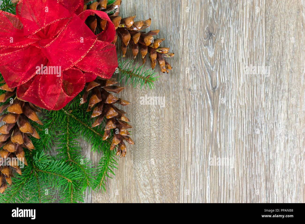 A red bow and three white pine cones on spruce boughs with copy space ...