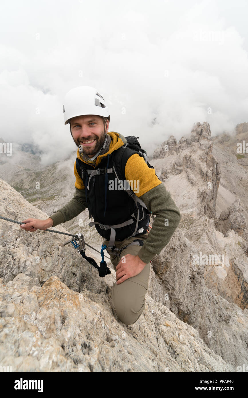 young male climber on a steep and exposed rock face climbing a Via ...