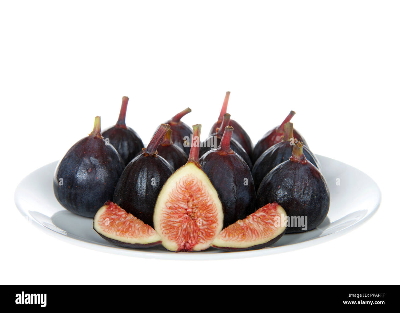 Fresh whole figs on an off white porcelain plate with sliced fig facing ...