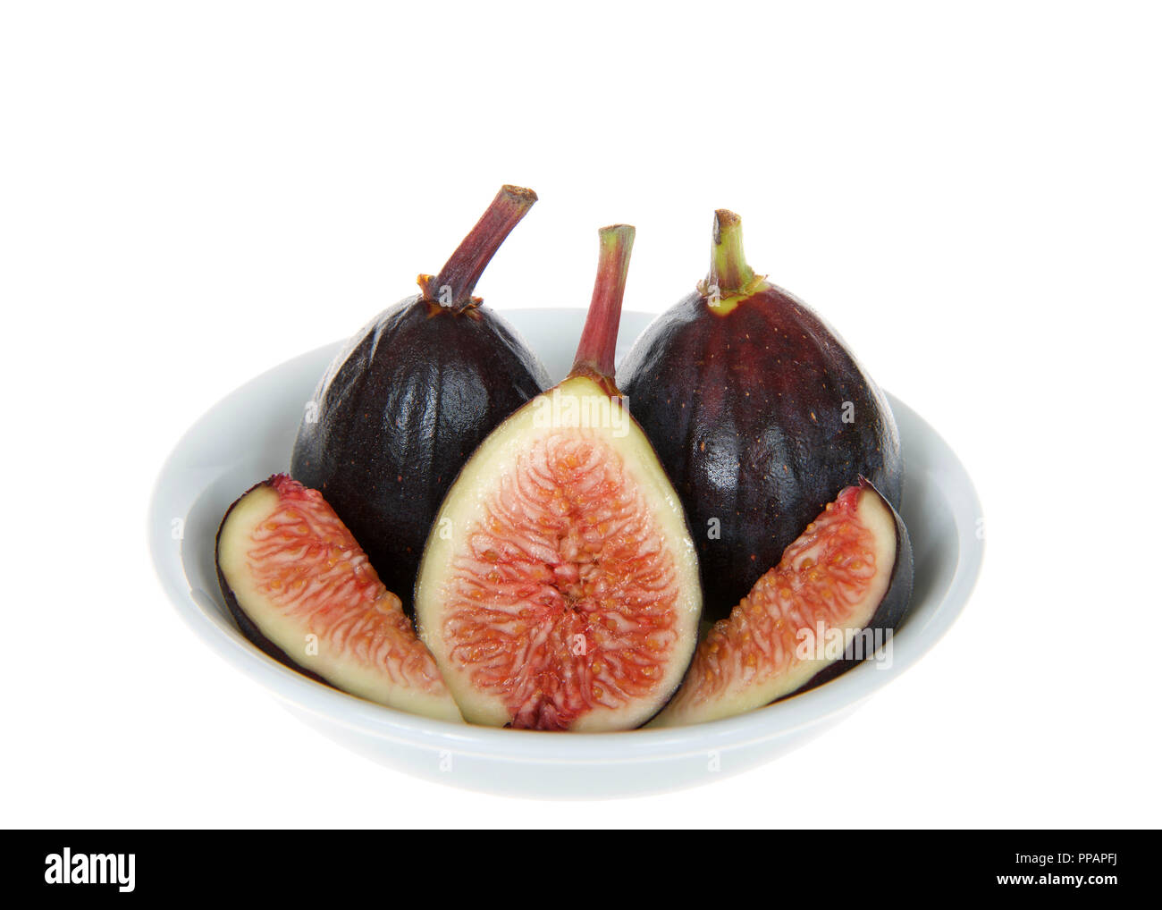 Fresh whole figs on an off white porcelain plate with sliced fig facing ...