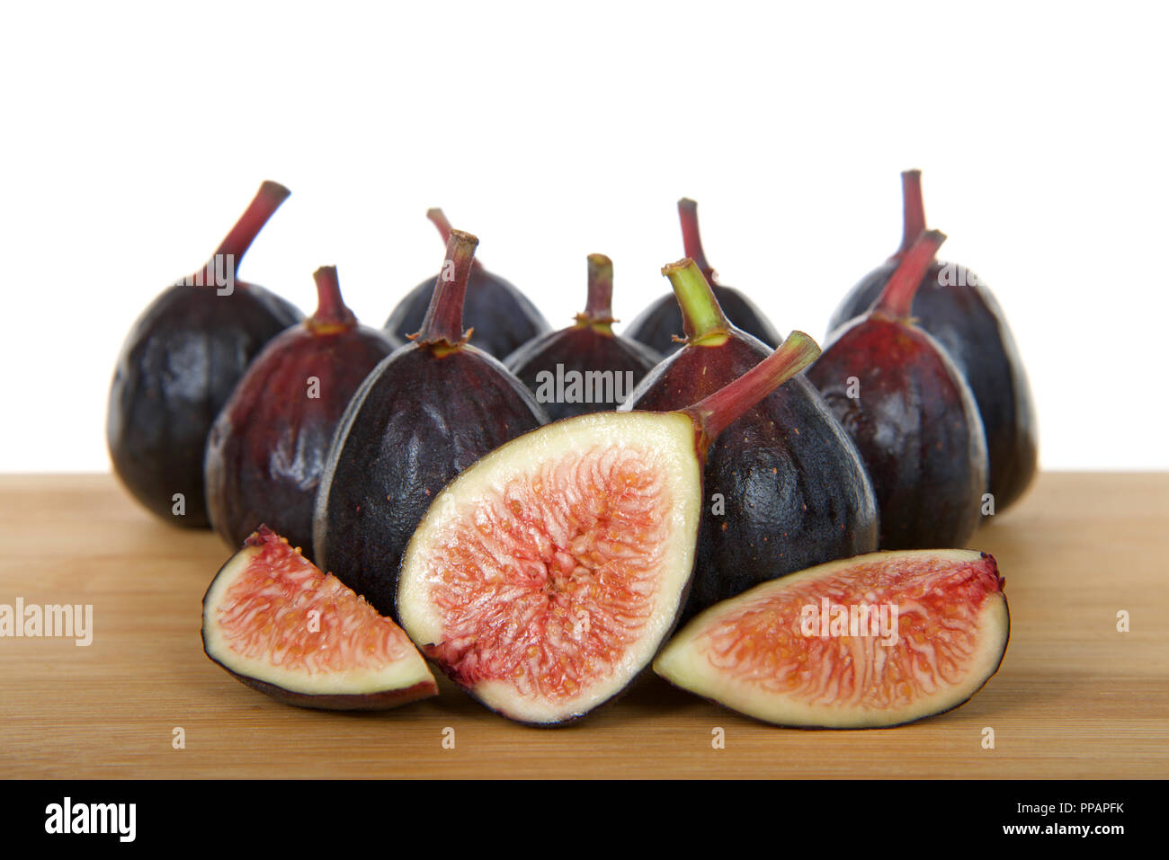 Fresh whole figs on an wood table with sliced figs facing viewer ...