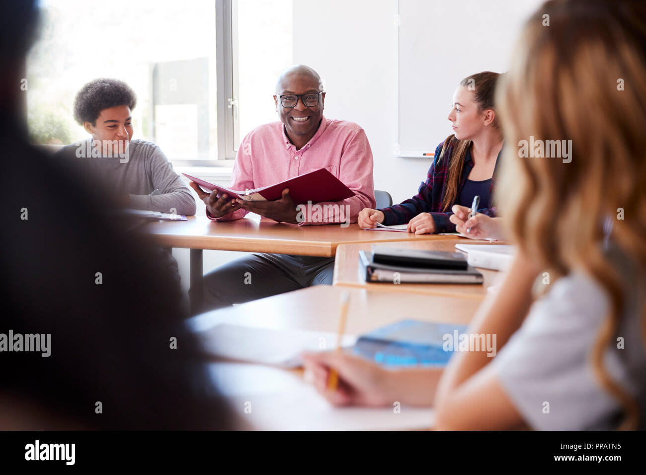 Male High School Tutor Sitting With Students At Desk In Class Stock ...