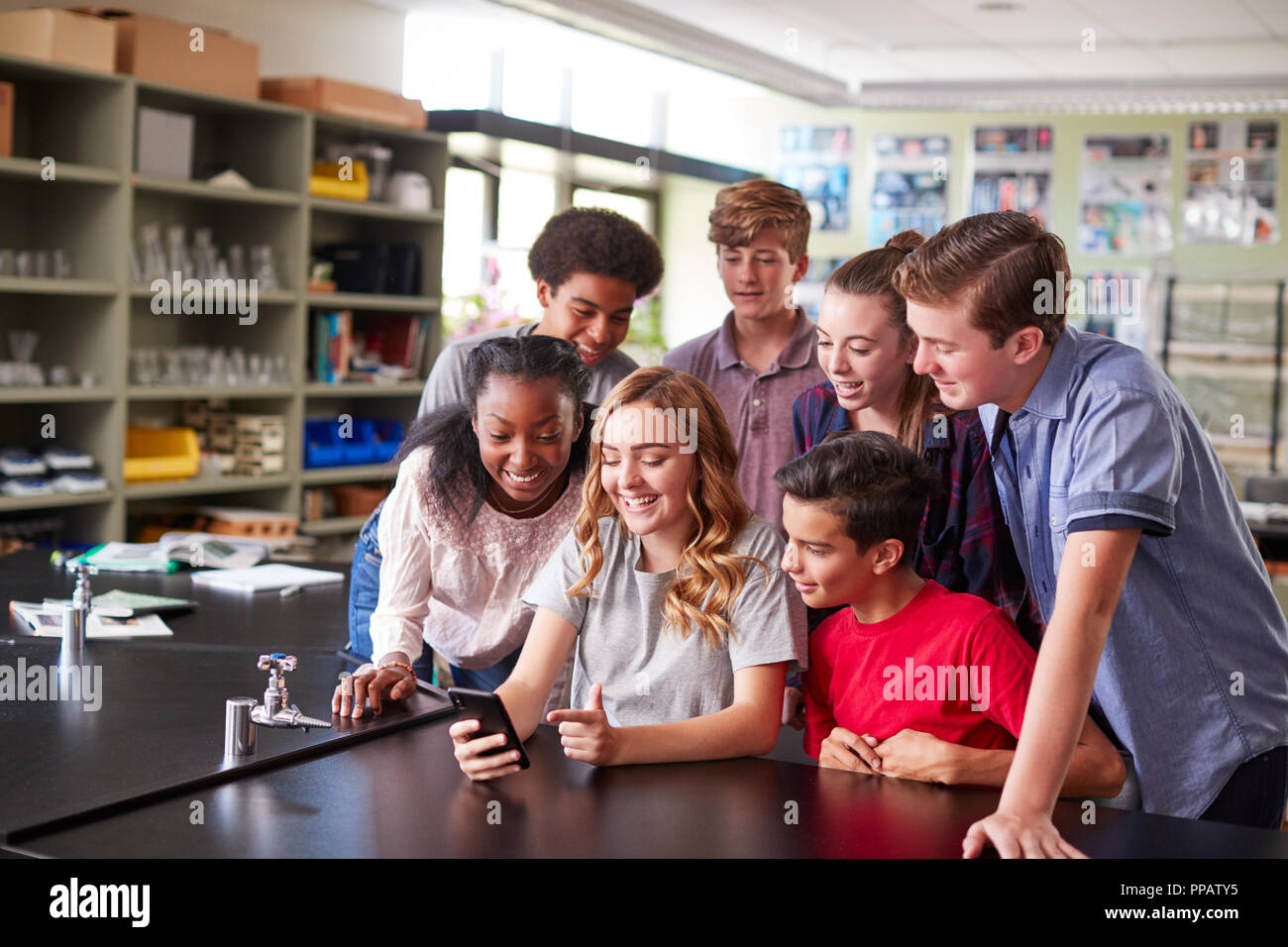 Group Of High School Students Looking At Message On Mobile Phone In ...