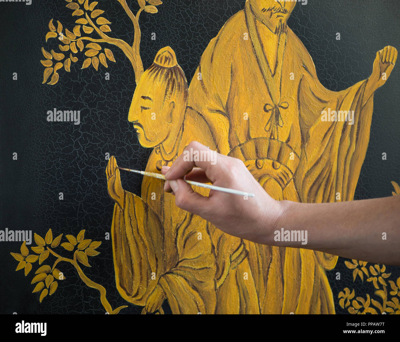 painter decorator draws Chinese pattern of leaves and man, macro ...