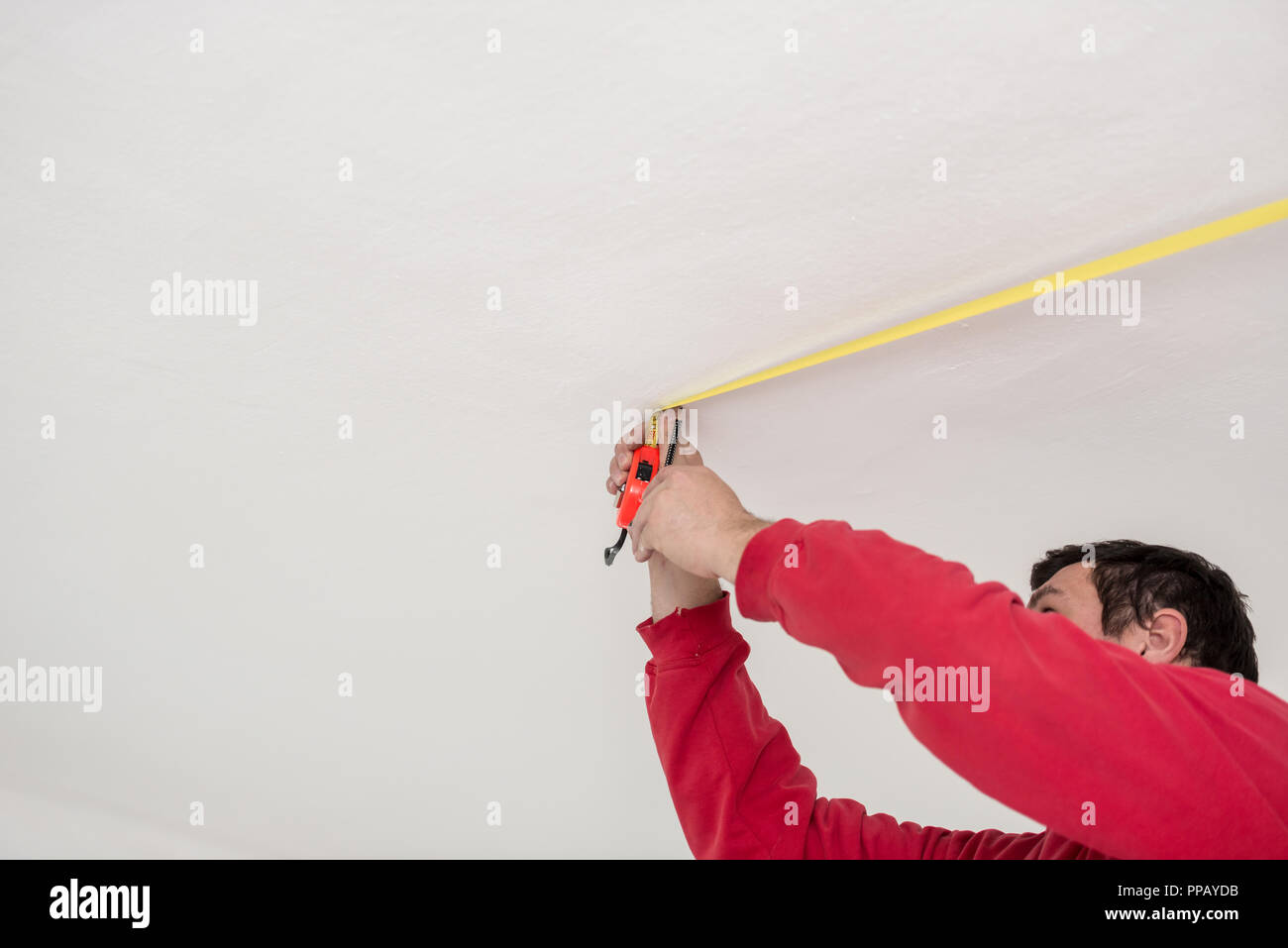 Builder taking a measurement with a tape marking a point on a white ...