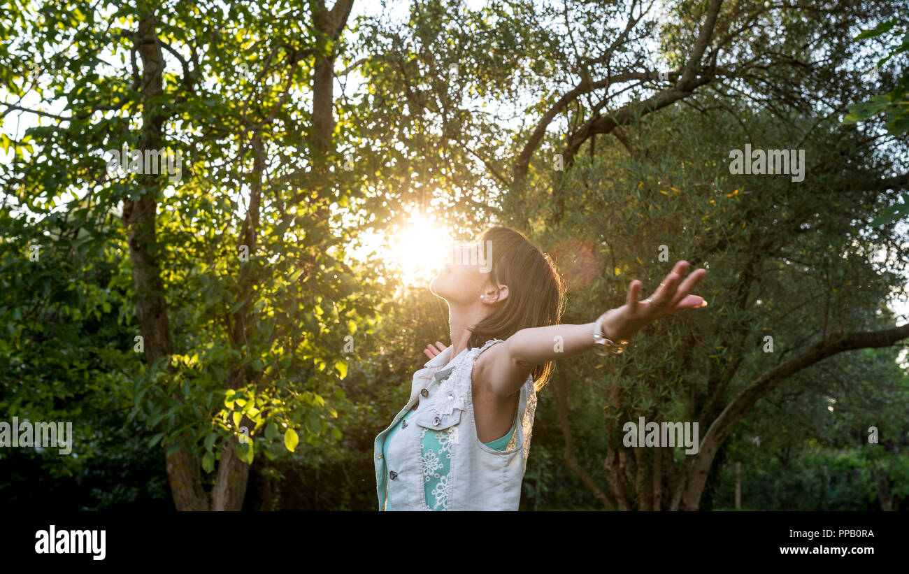 Woman meditating in nature standing with outspread arms as the rising ...