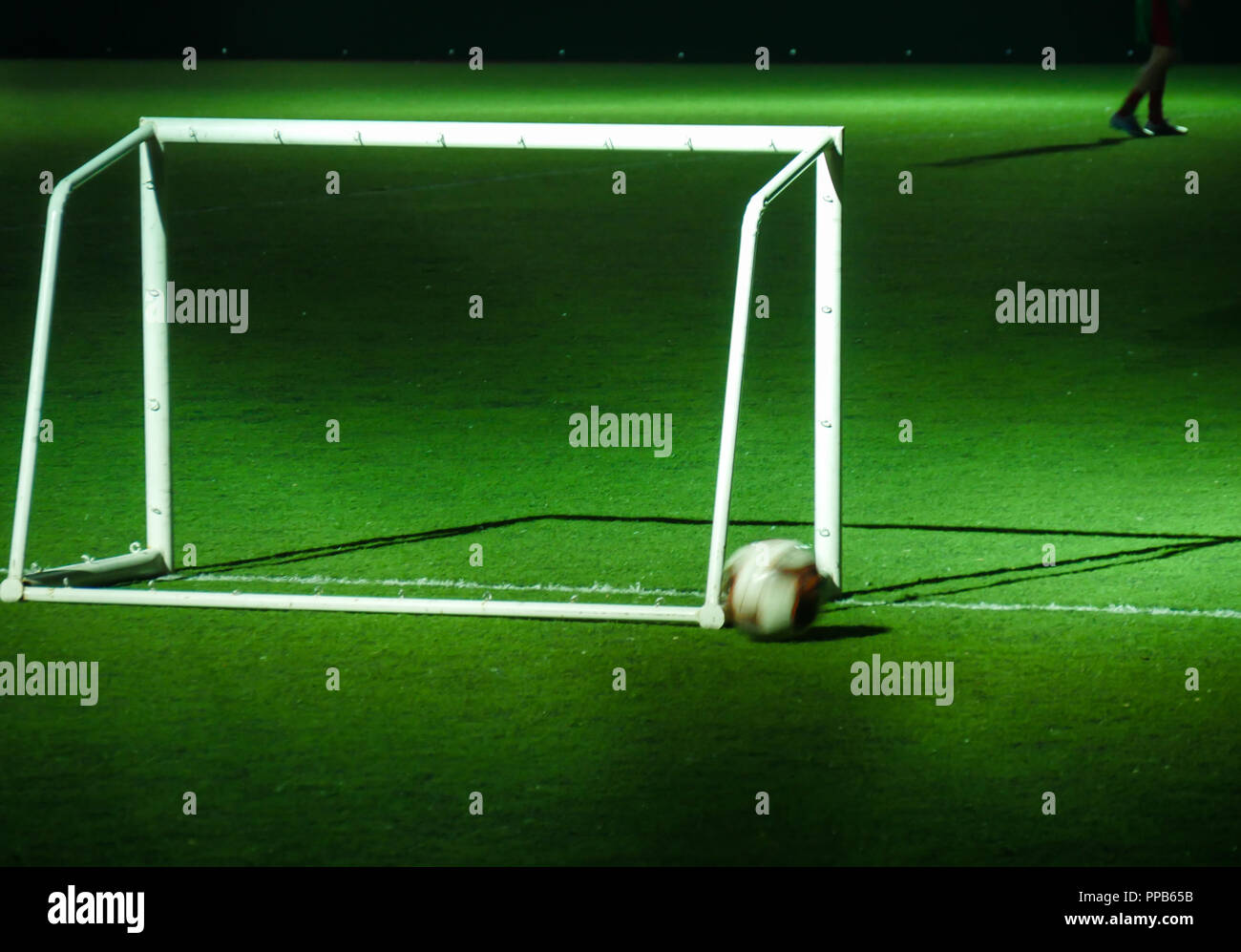 Soccer ball and goalpost on green soccer pitch at night Stock Photo - Alamy