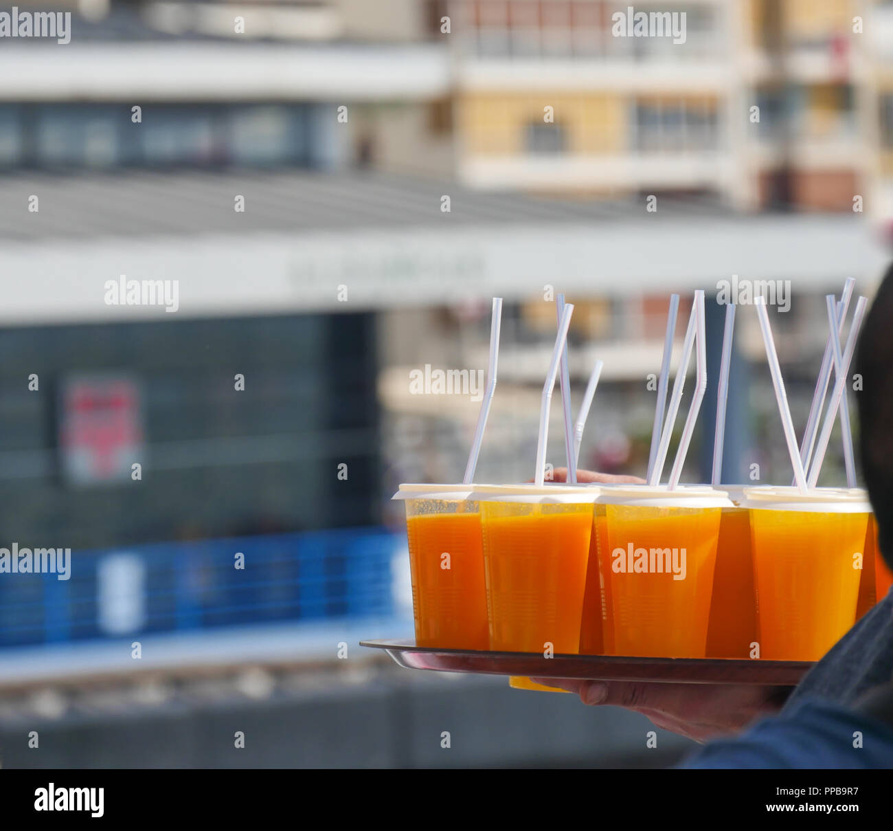 A waiter with a tray of cup of Orange juice Stock Photo - Alamy