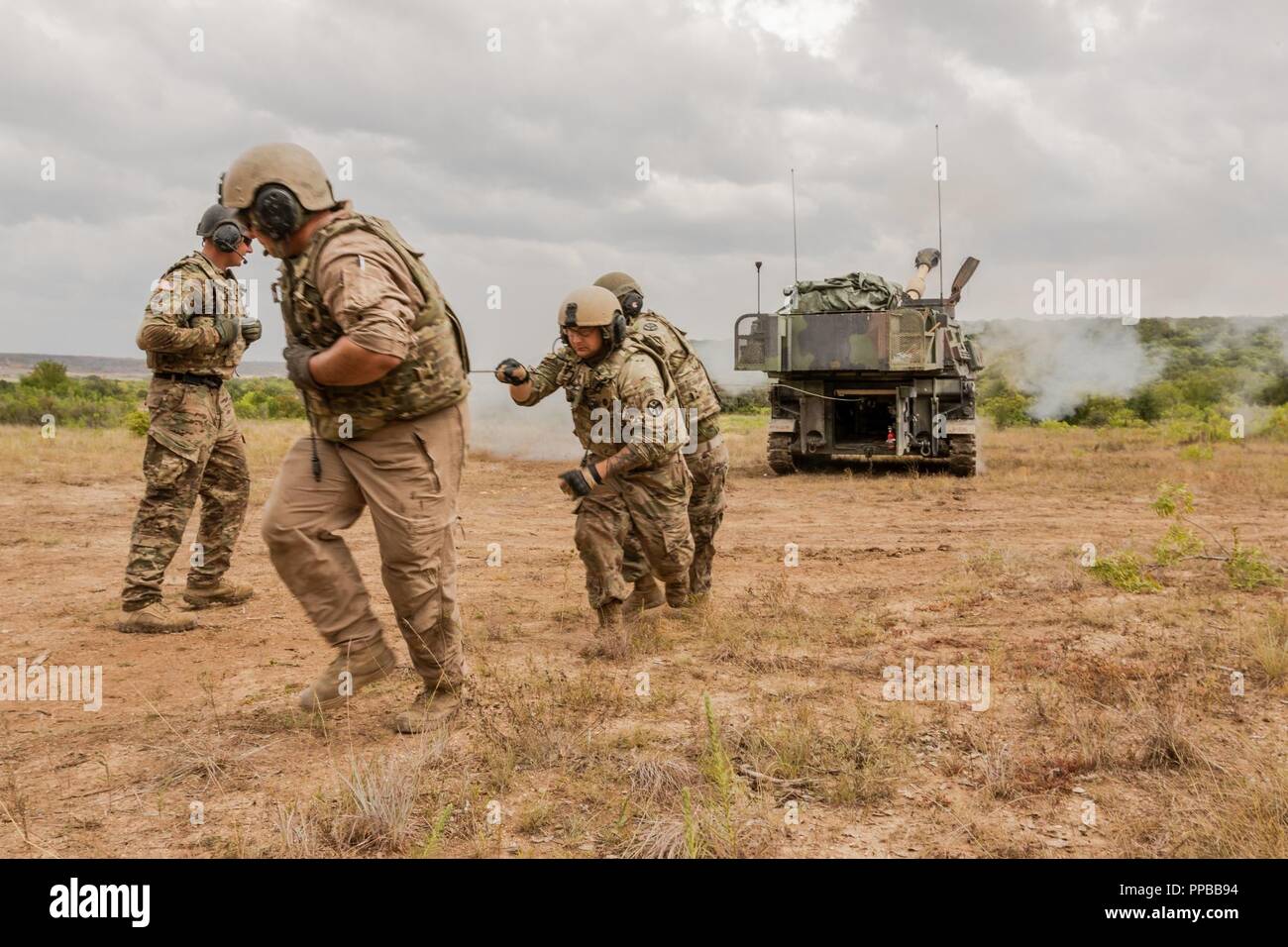 U.S. Army M109 Paladin artillery crew-members pull the 50-meter lanyard ...