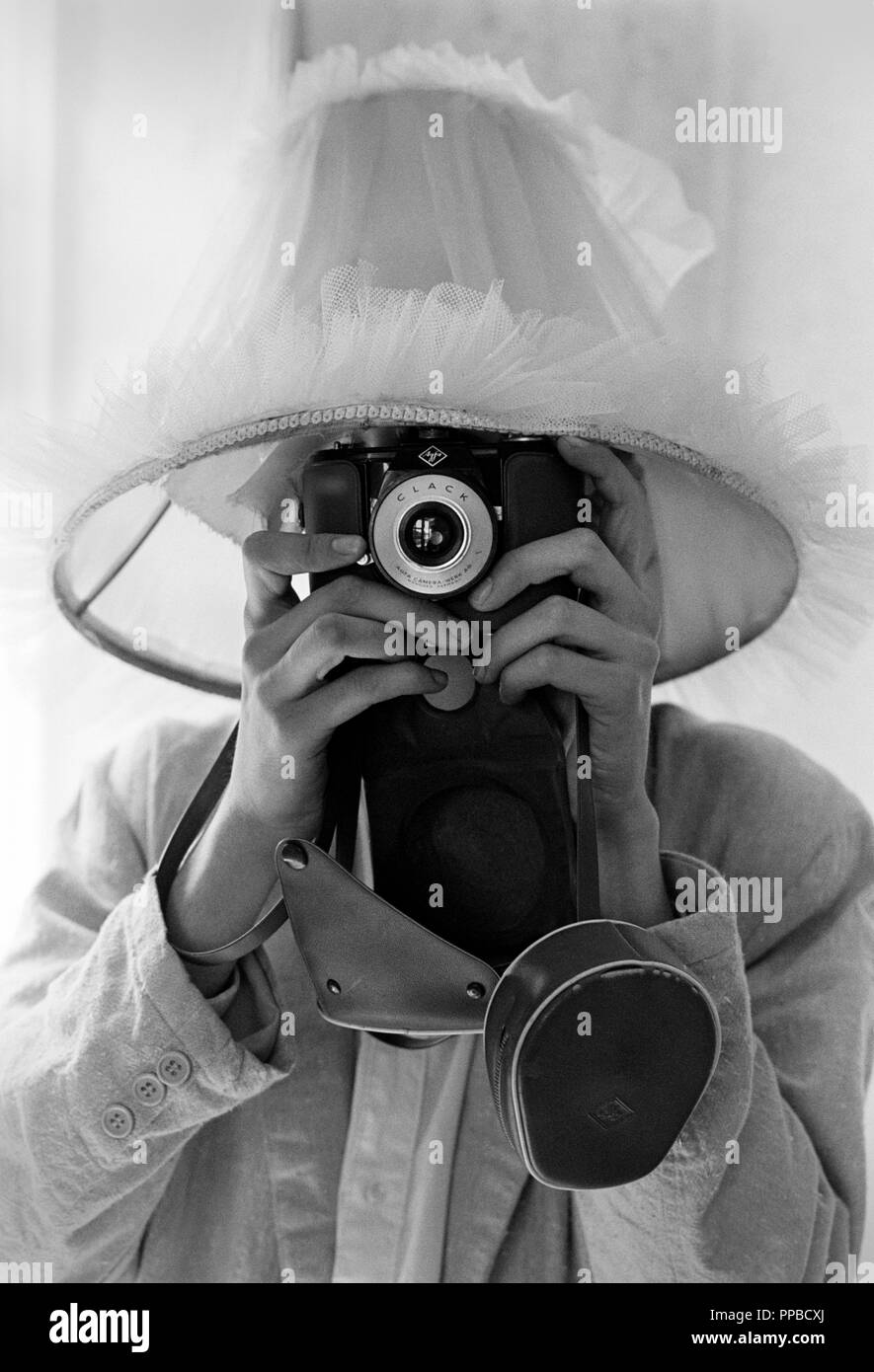 photographer hiding under a lamp-shade with retro camera Stock Photo ...