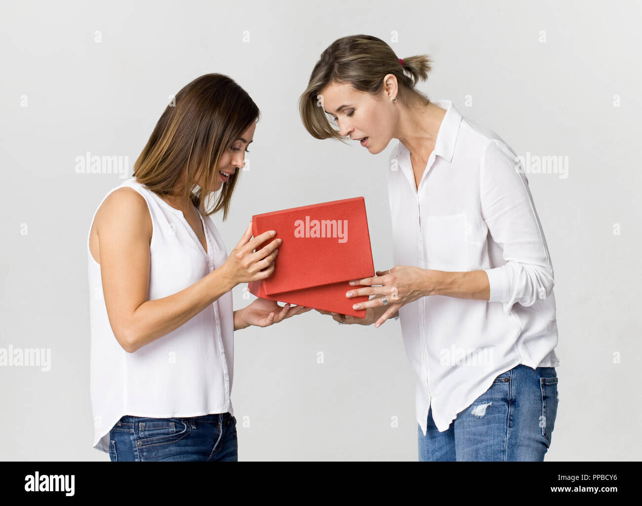 Surprised young woman gets a gift from her friend. Happy and smiling ...