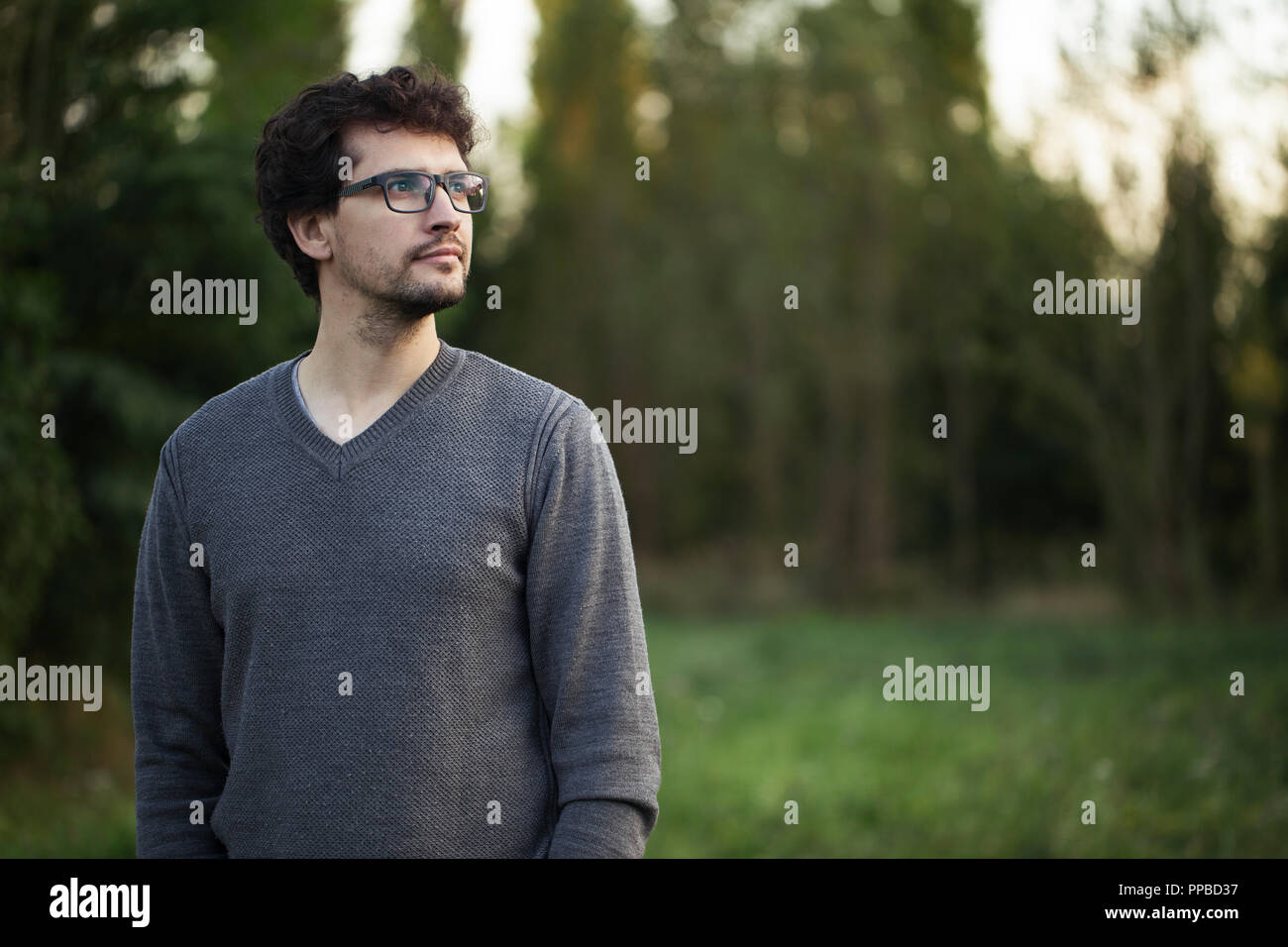 Calm man standing in the park looking to the left Stock Photo - Alamy