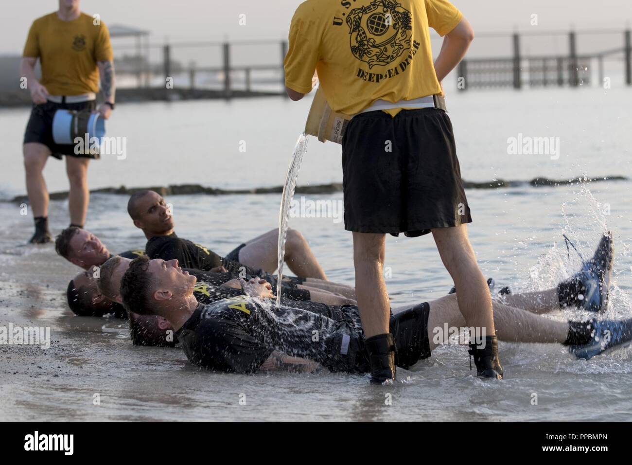 A U.S. Army Soldier flutter kicks in shallow water as his team watches ...