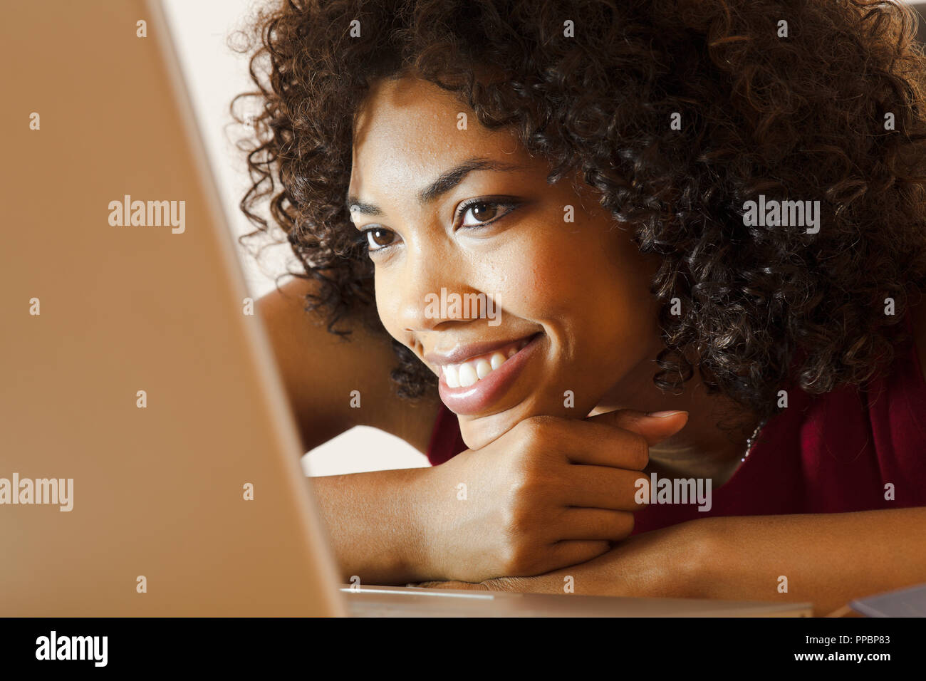 Close up portrait of happy millennial black woman looking at computer ...