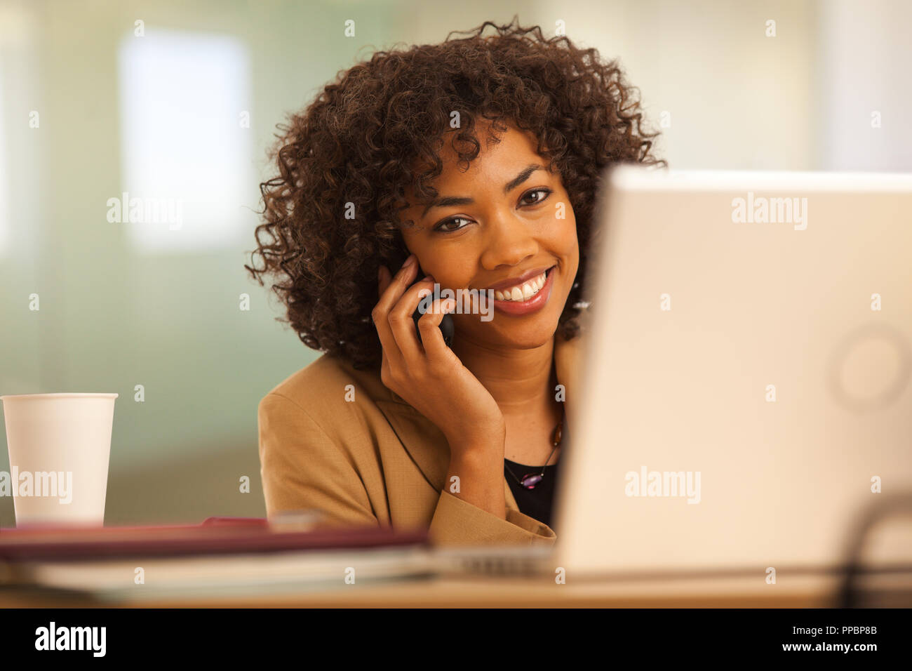 Millennial businesswoman using laptop computer while talking on phone ...