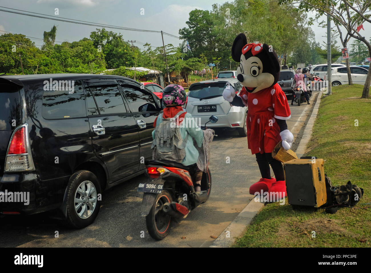 An artist is seen entertaining motorists passing on the highway wearing ...